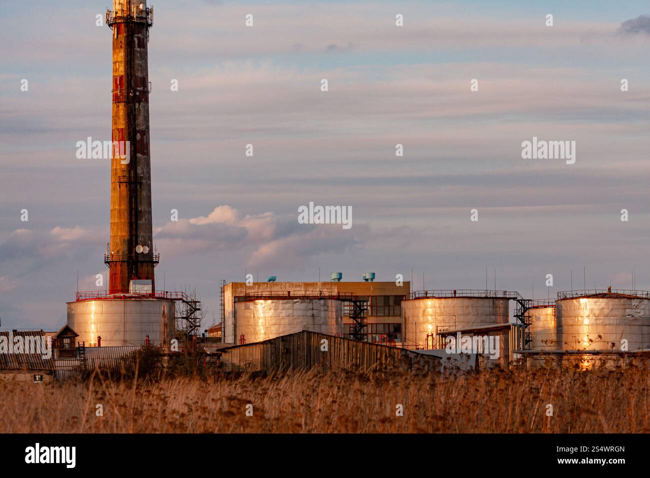 Industrial refinery with storage tanks and a tall smoke stack ...