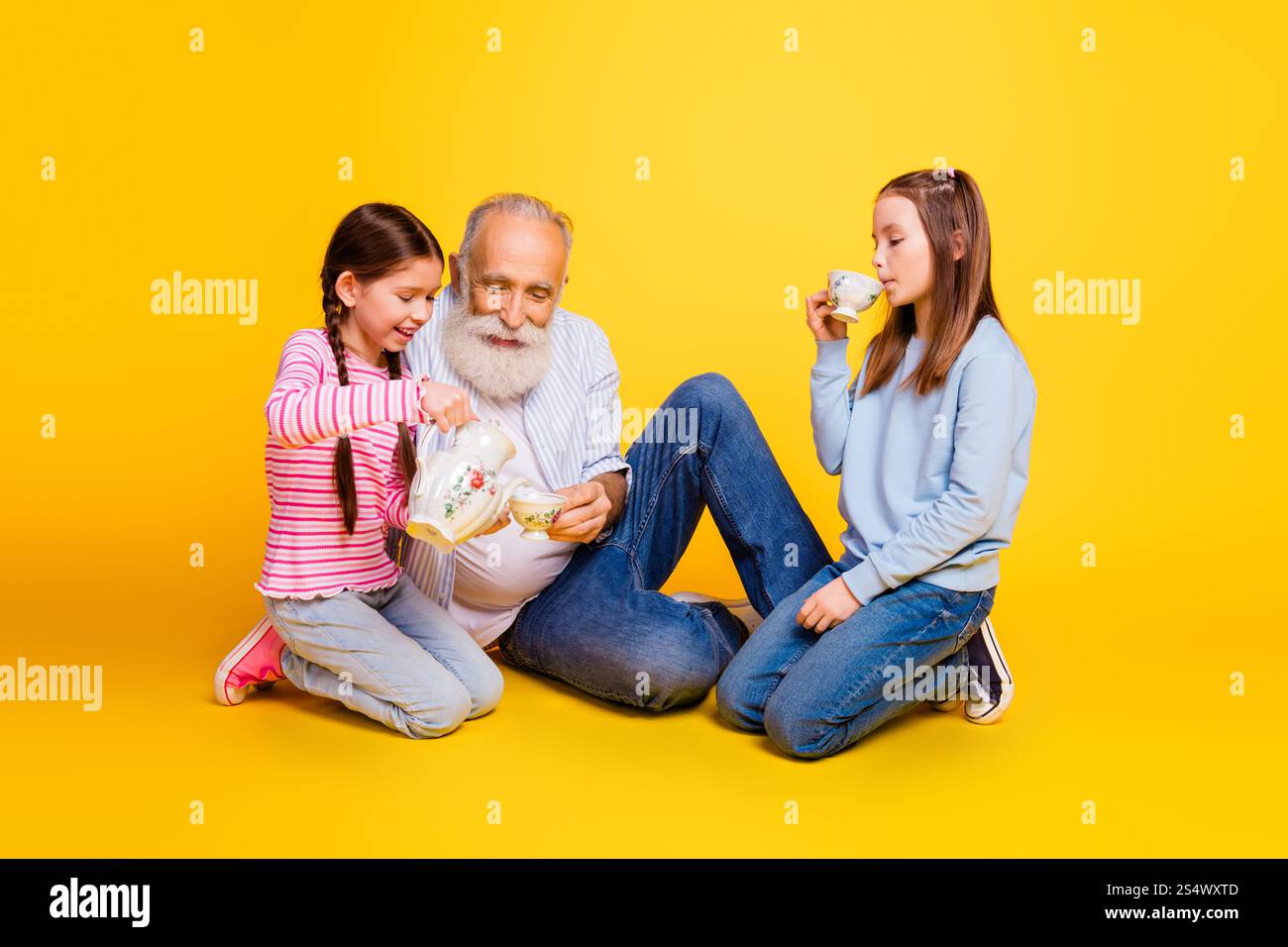Family bonding time with grandfather and granddaughters enjoying tea ...