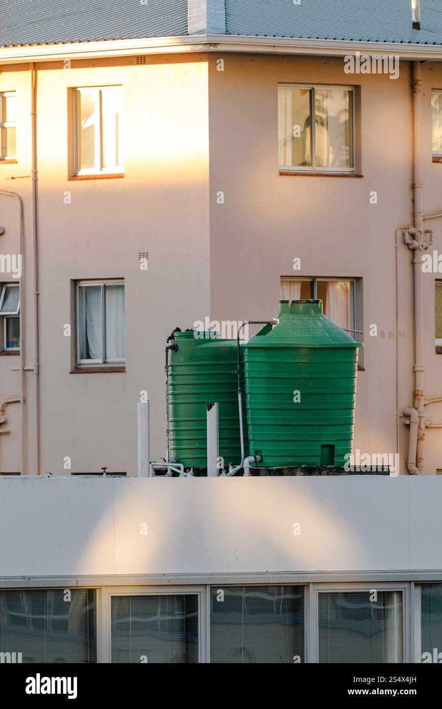 Two large, green plastic cylindrical water tanks are positioned on a ...