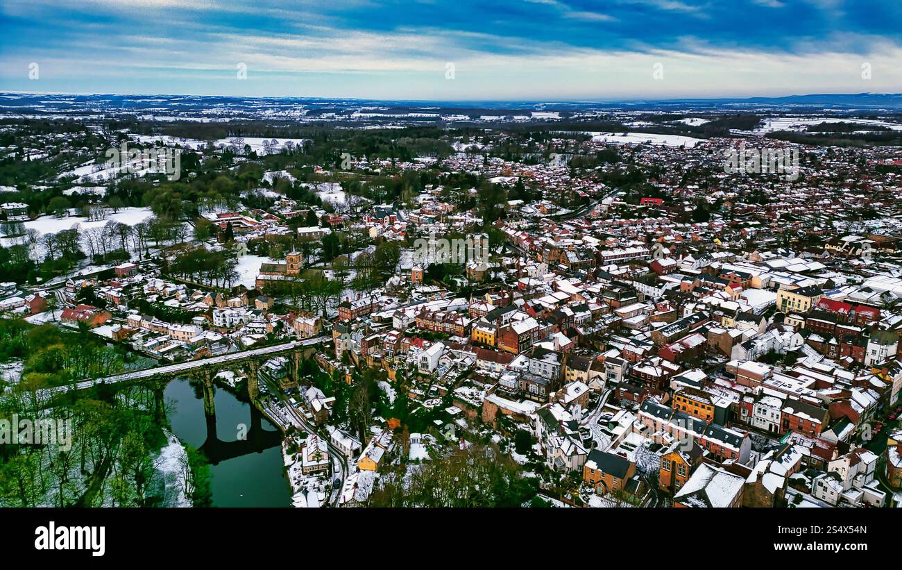 Aerial view of a snow-covered town with a viaduct and river. Buildings ...