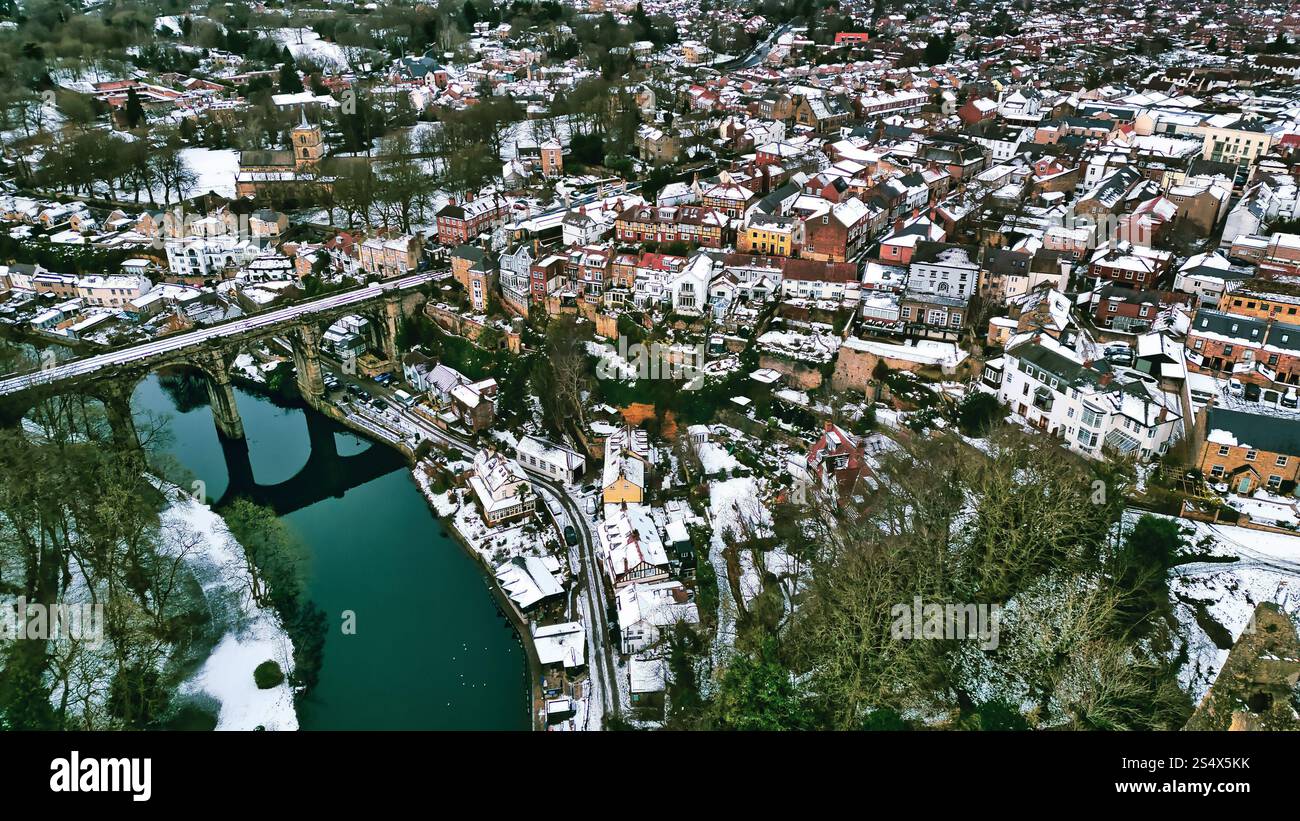 Aerial view of a snow-covered town with a river and a stone viaduct ...