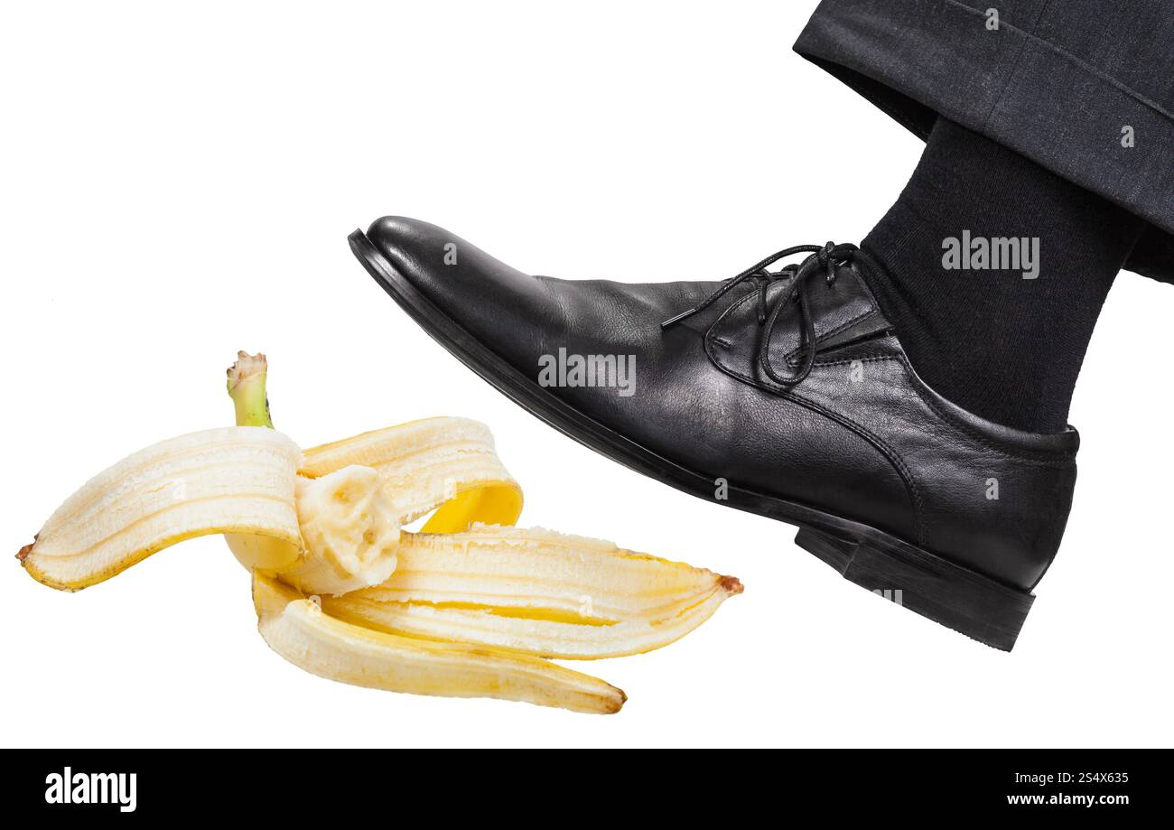male leg in the left black shoe slips on a banana peel isolated on ...