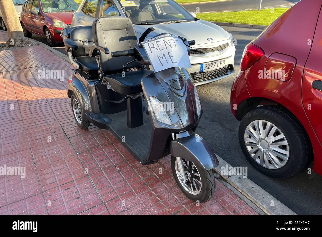 A two-seater Mobility Scooter with a makeshift paper sign saying "Rent ...