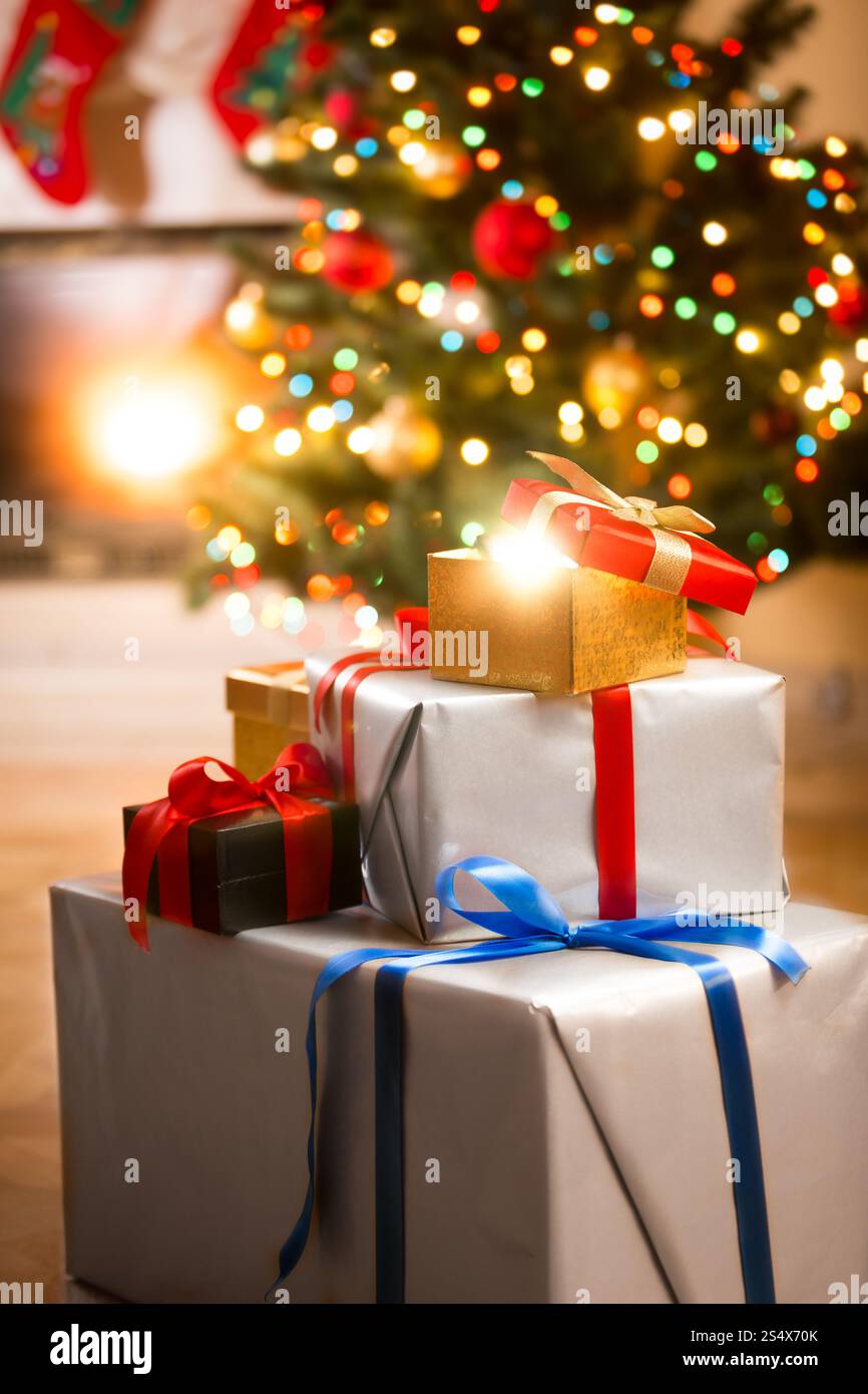 Stack of gift boxes under Christmas tree next to fireplace at living ...