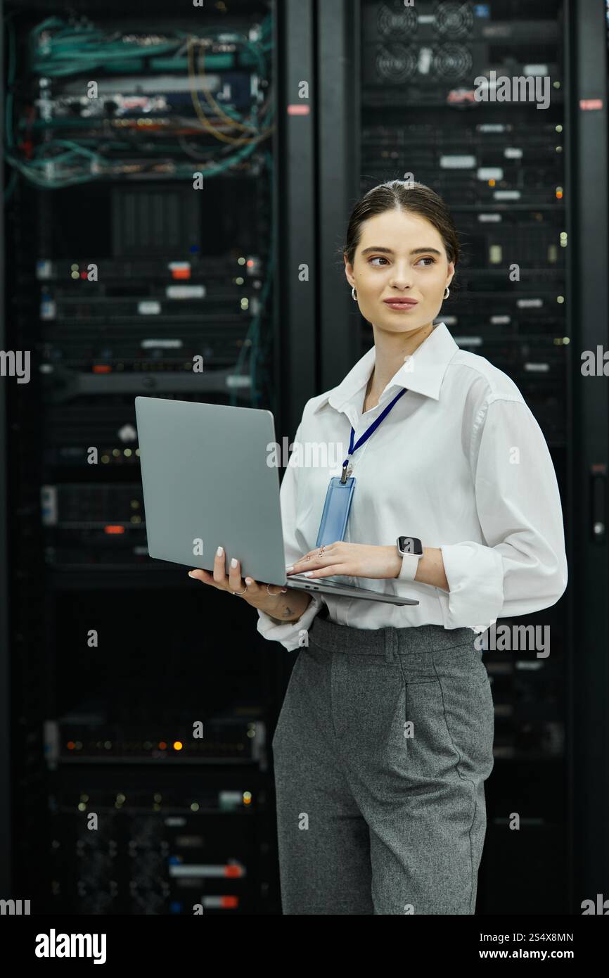 A woman in a white shirt works on her laptop in a modern server room ...