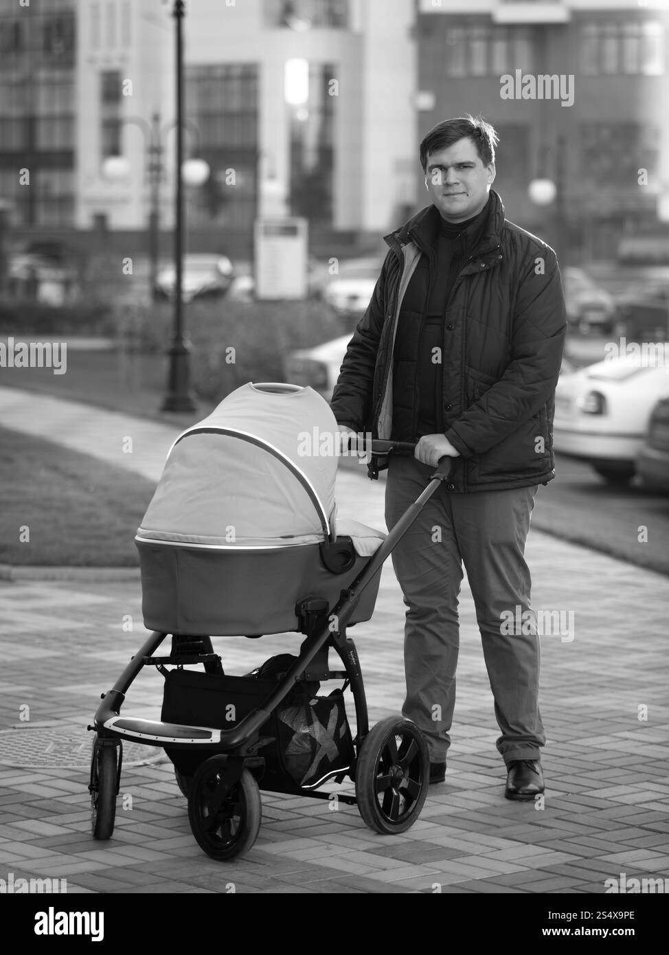 Black and white photo of young happy father walking with baby in pram ...