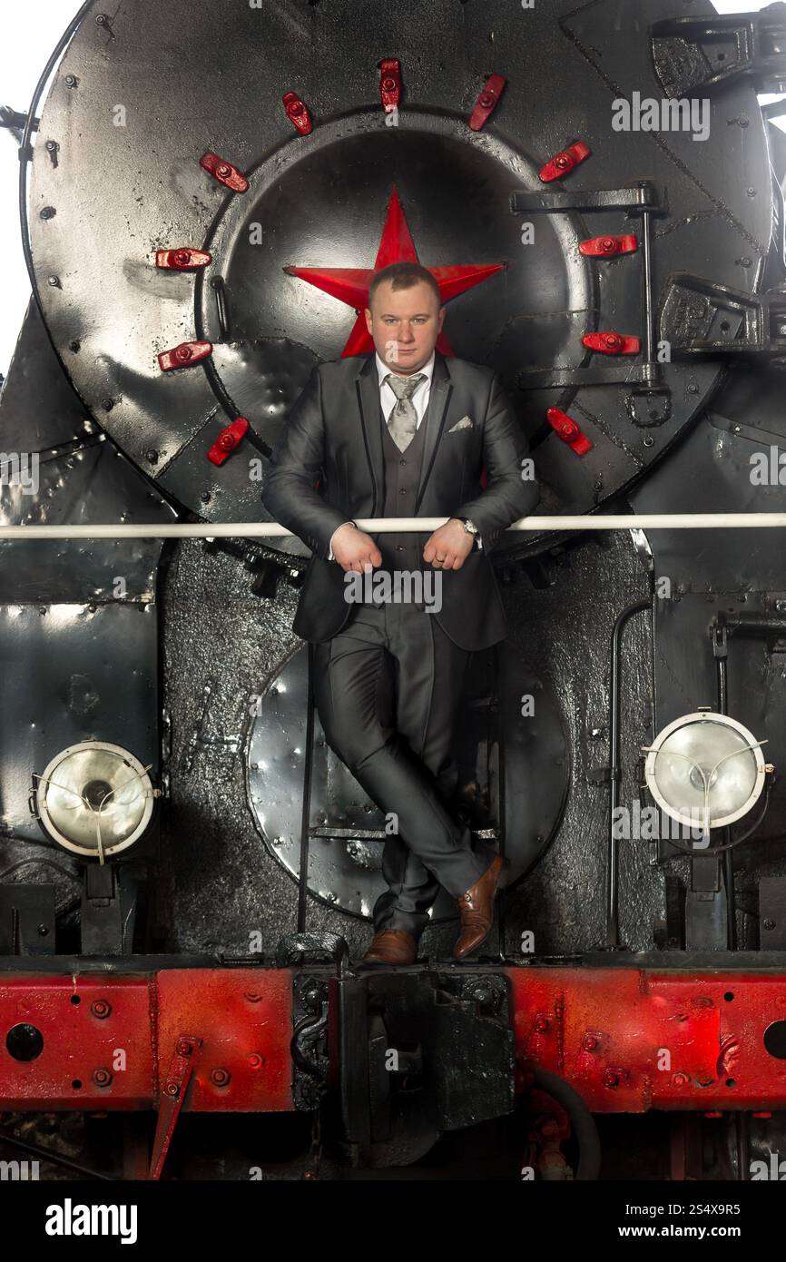 Retro styled businessman in suit posing on soviet steam locomotive ...