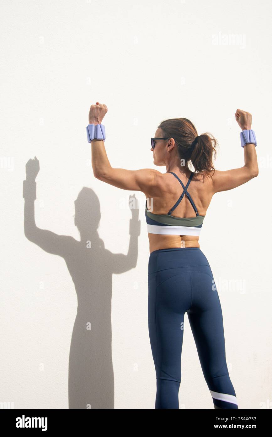 sporty mid adult woman doing arm exercises outdoors using adustable ...