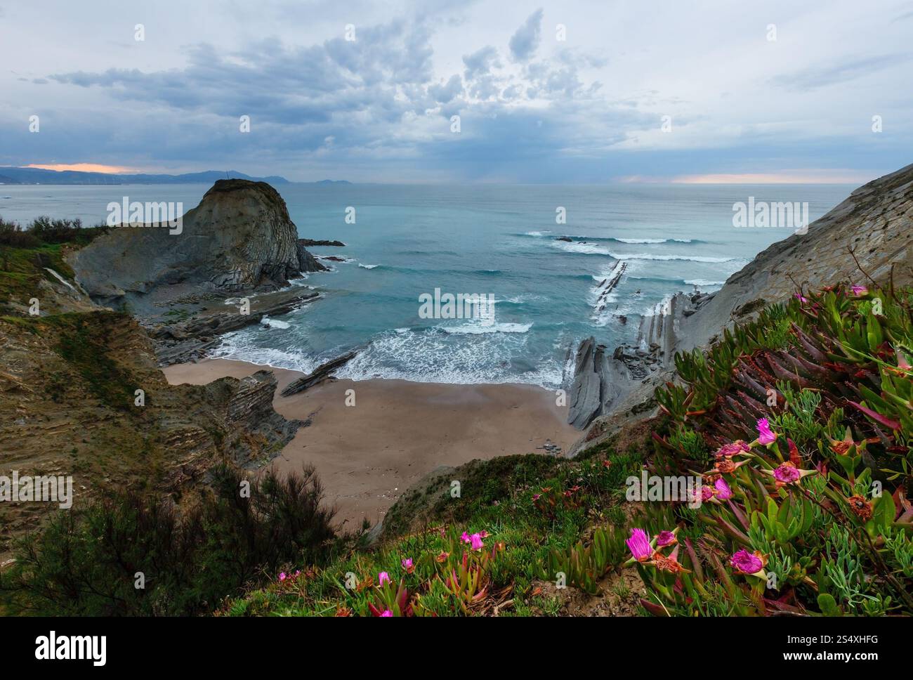 Spring sunset sea rocky coast landscape with small sandy beach and pink ...