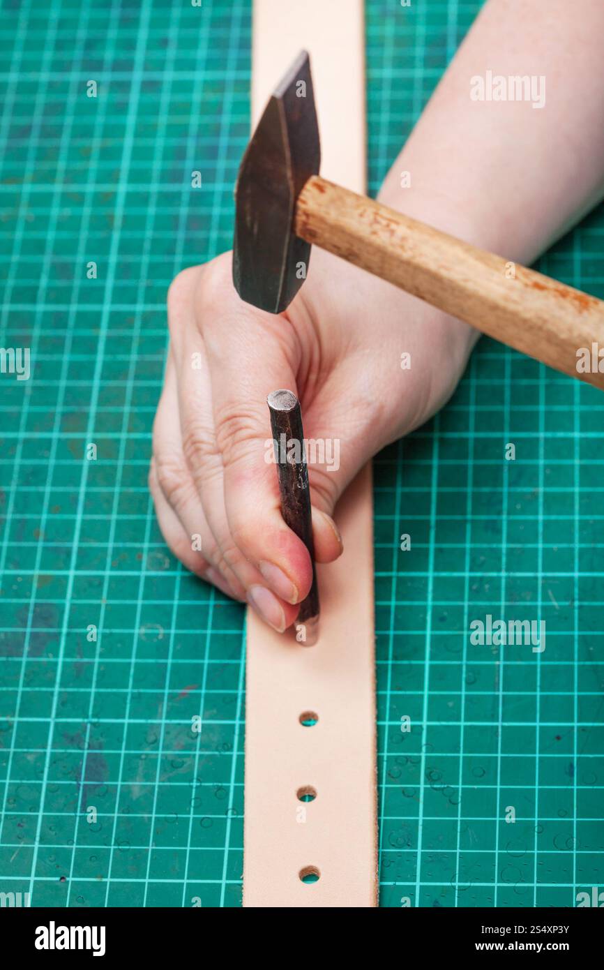 hole punch and hammer make hole in belt on self-healing mat Stock Photo ...