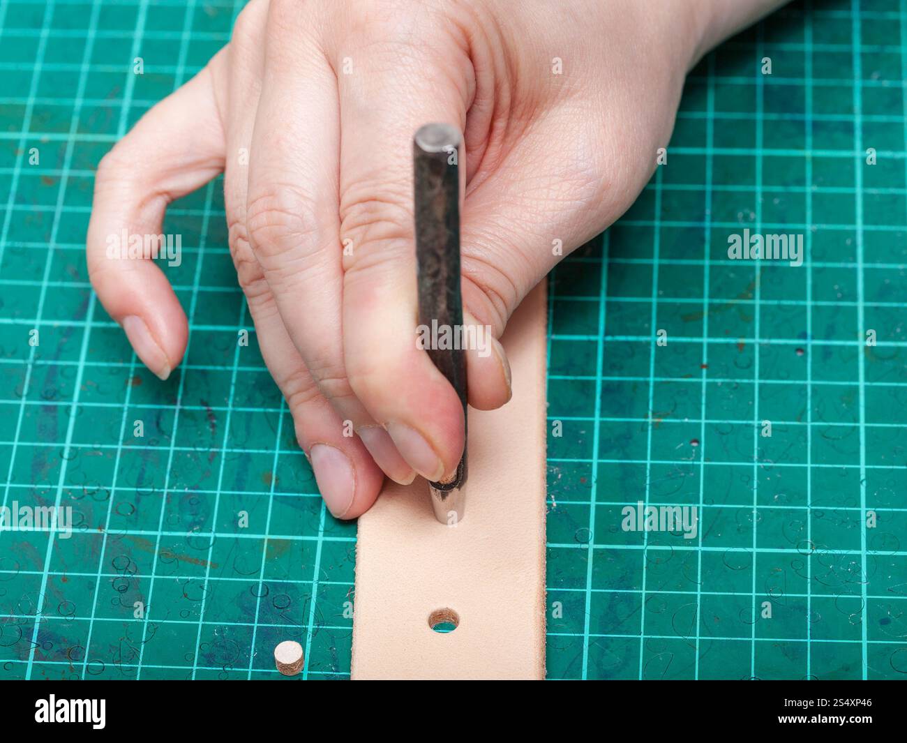 punching hole in new belt with steel punch on self-healing mat Stock ...
