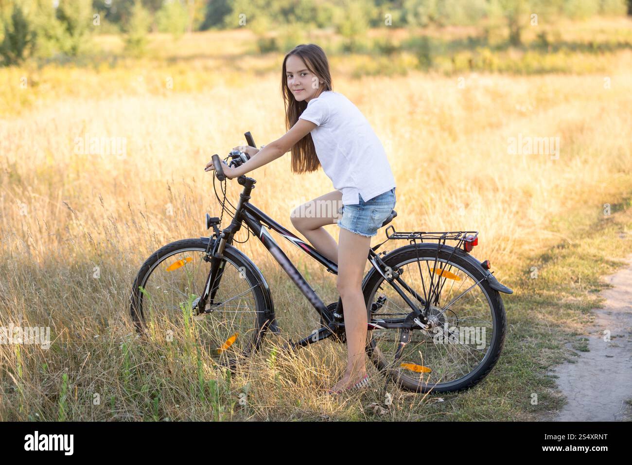 Beautiful teenage girl posing on bicycle in field at hot sunny day Stock Photo - Alamy