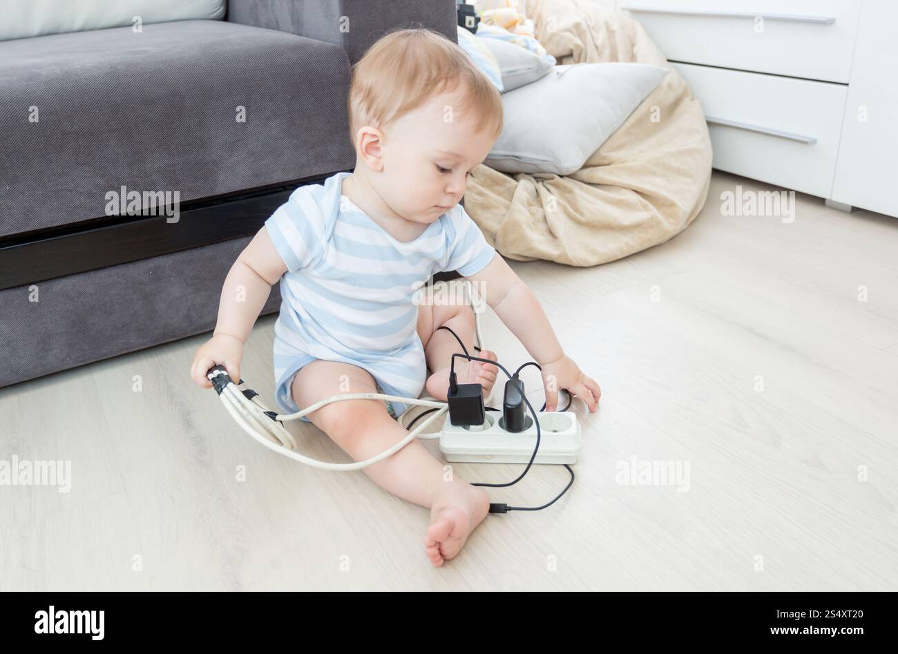 Adorable baby boy playing with electrical extension and wires on floor ...