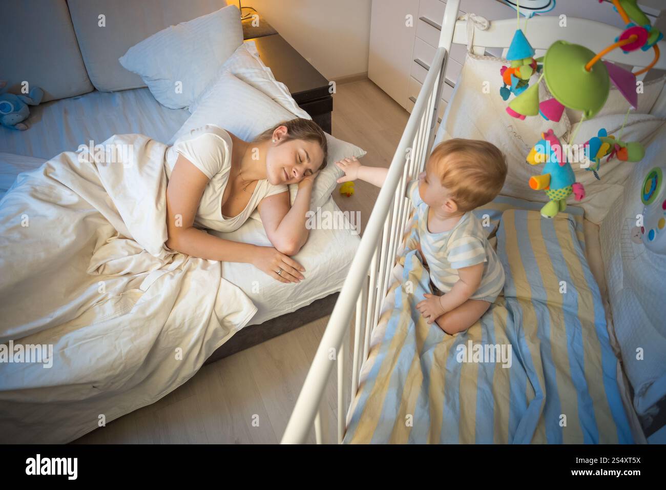 Crying baby boy waking up and reaching his mother at night Stock Photo ...