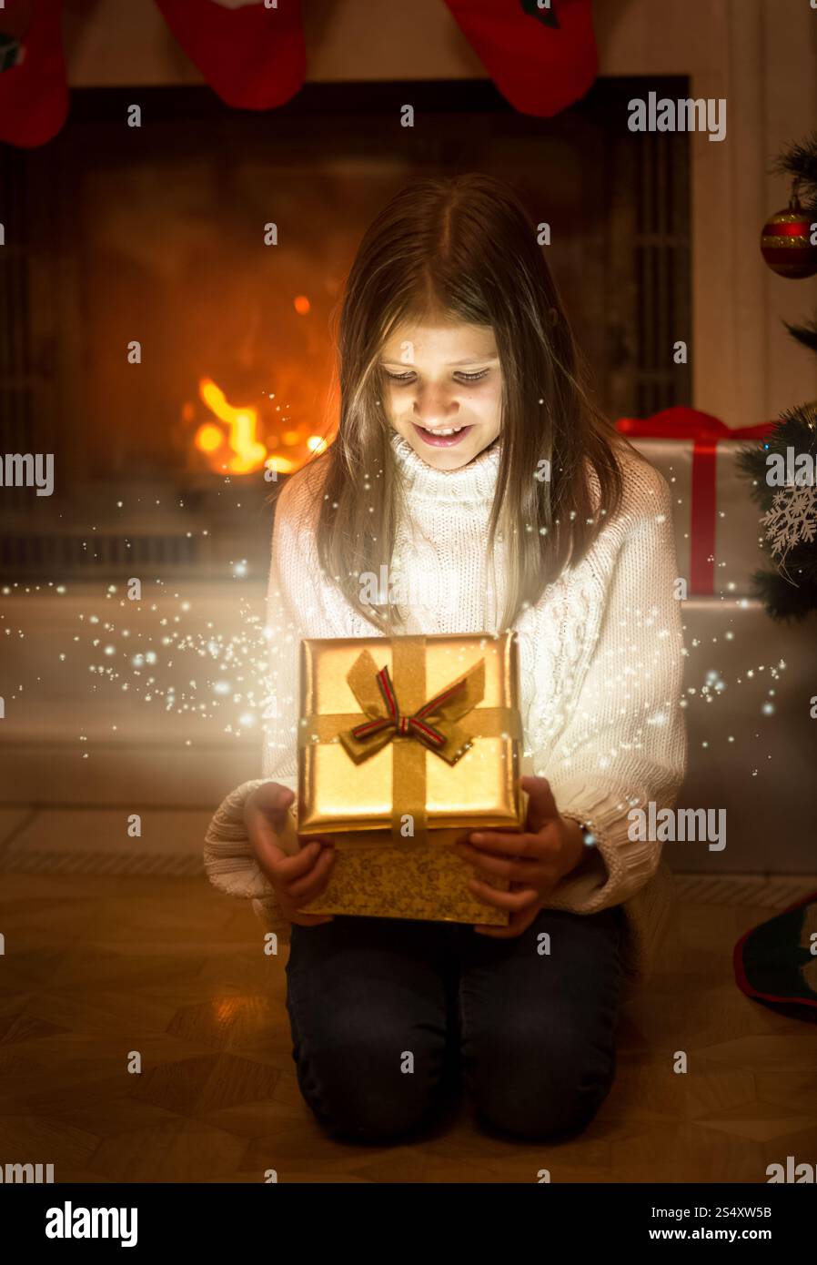 Portrait of happy smiling girl opening shiny Christmas gift box. Light ...
