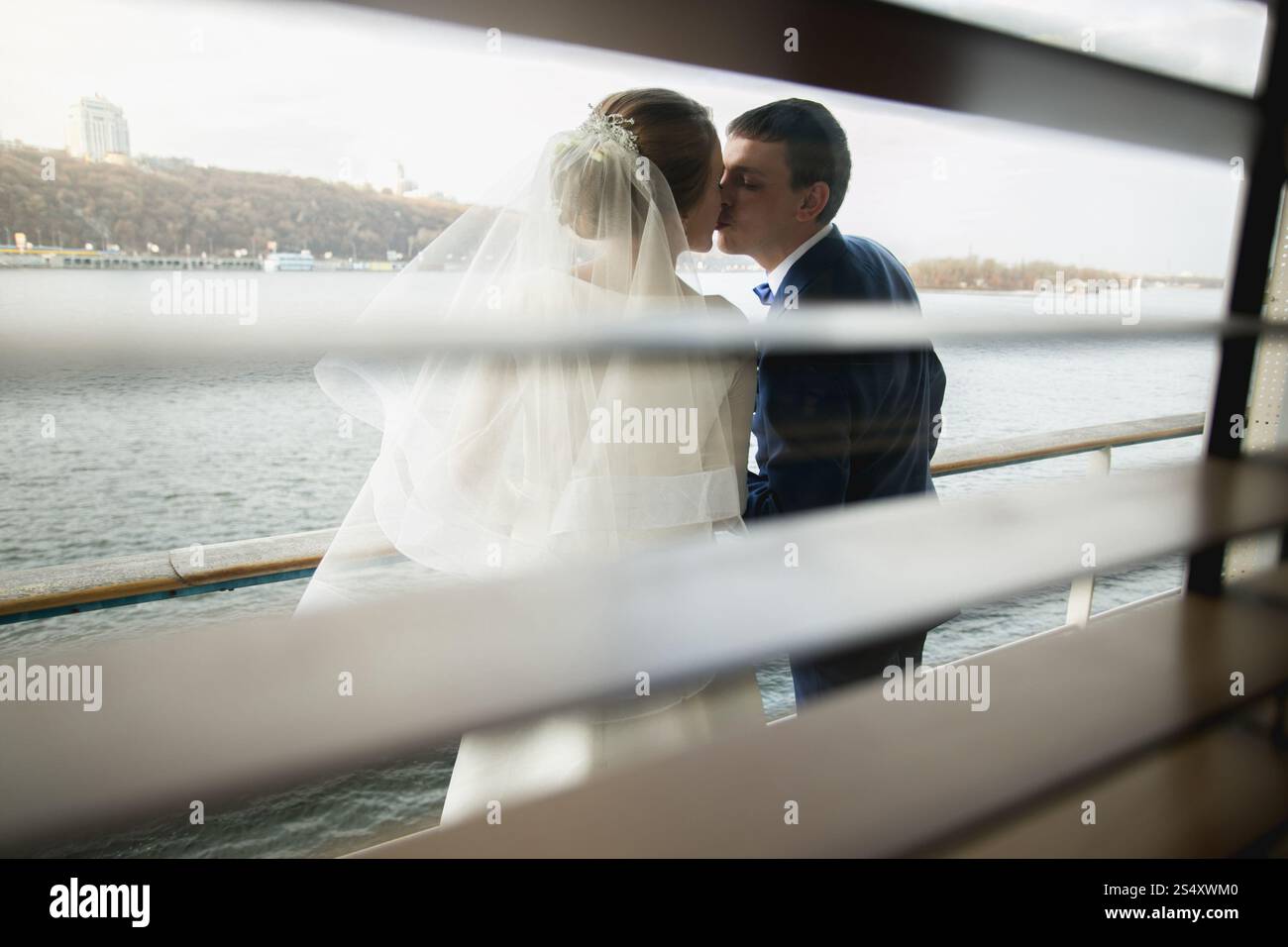 Portrait through window jalousie of kissing happy newly married couple ...