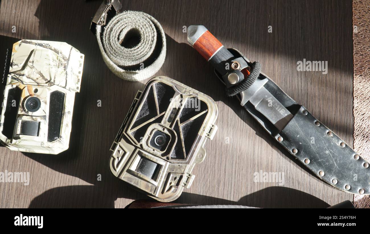 Hunting rifle with hunting equipment on a wooden table, sunlight is ...