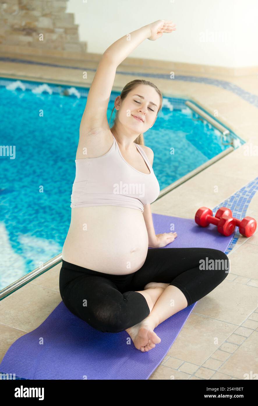Young pregnant woman posing on blue fitness mat at swimming pool Stock ...