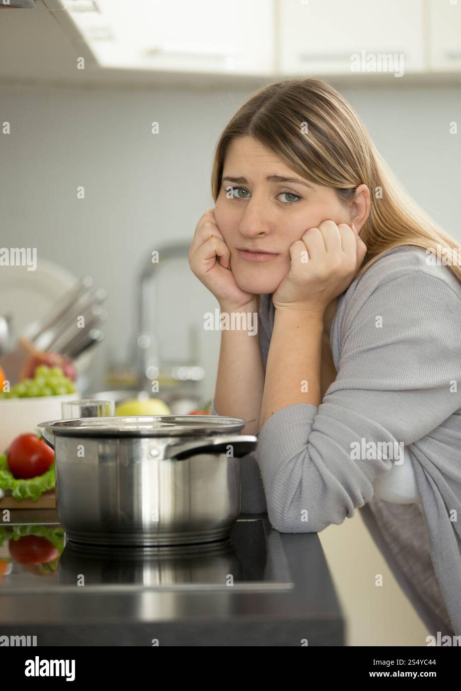 Portrait of sad woman leaning on table at kitchen while cooking Stock ...