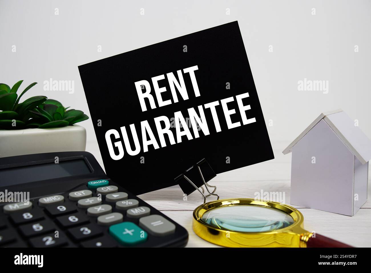 Rent Guarantee text message on sticky note with alarm clock, magnifying ...