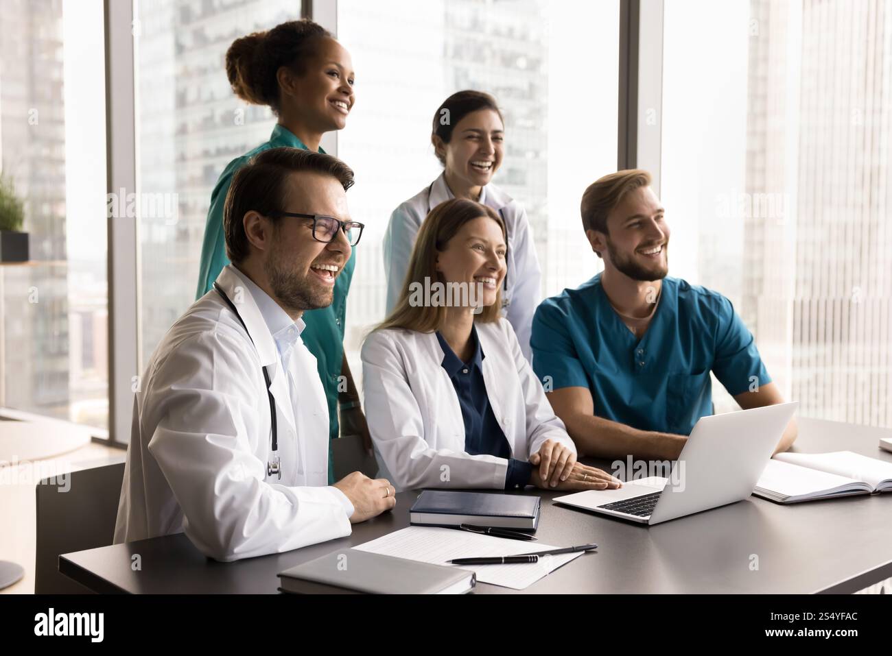 Five laughing doctors laughing, gathered together in modern conference ...