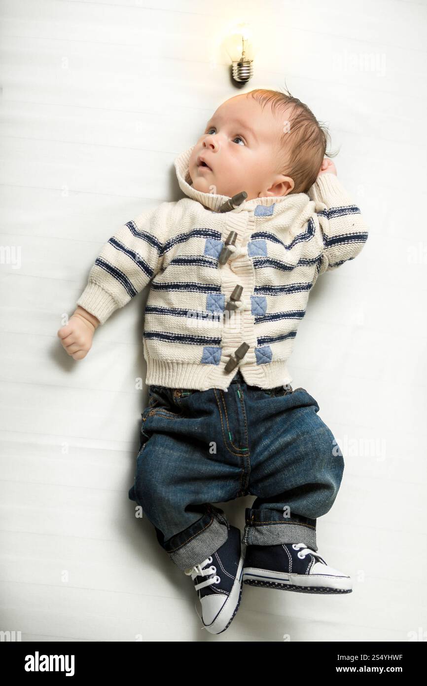 Cute baby boy posing on bed with glowing light bulb overhead Stock ...