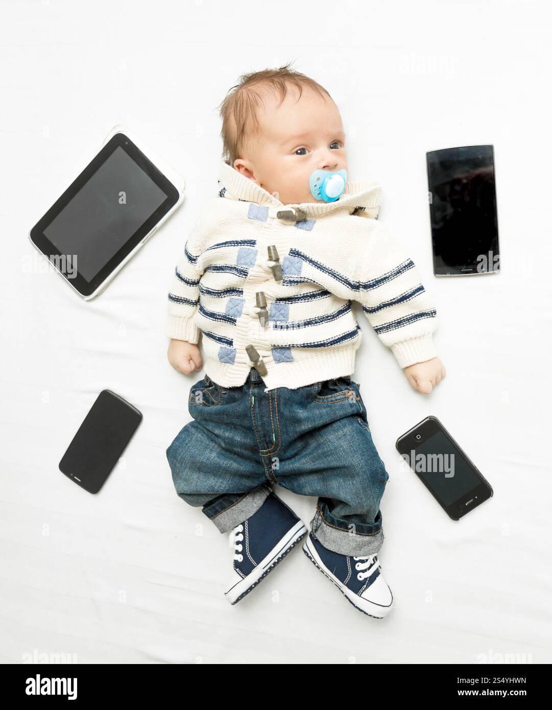 Cute baby boy lying on bed with smartphones, Concept of modern ...
