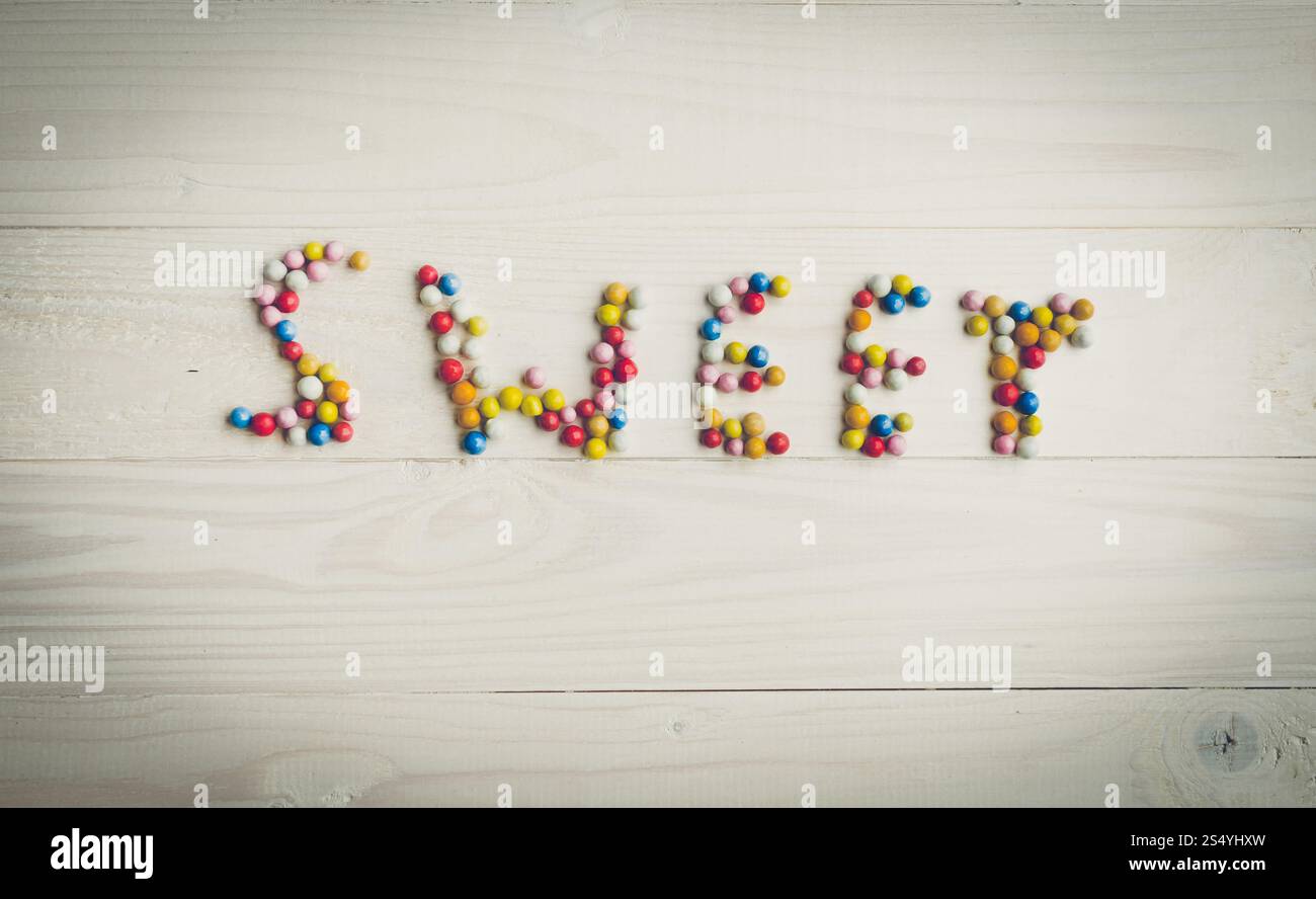Toned image of word Sweet made of colorful candies on white background ...