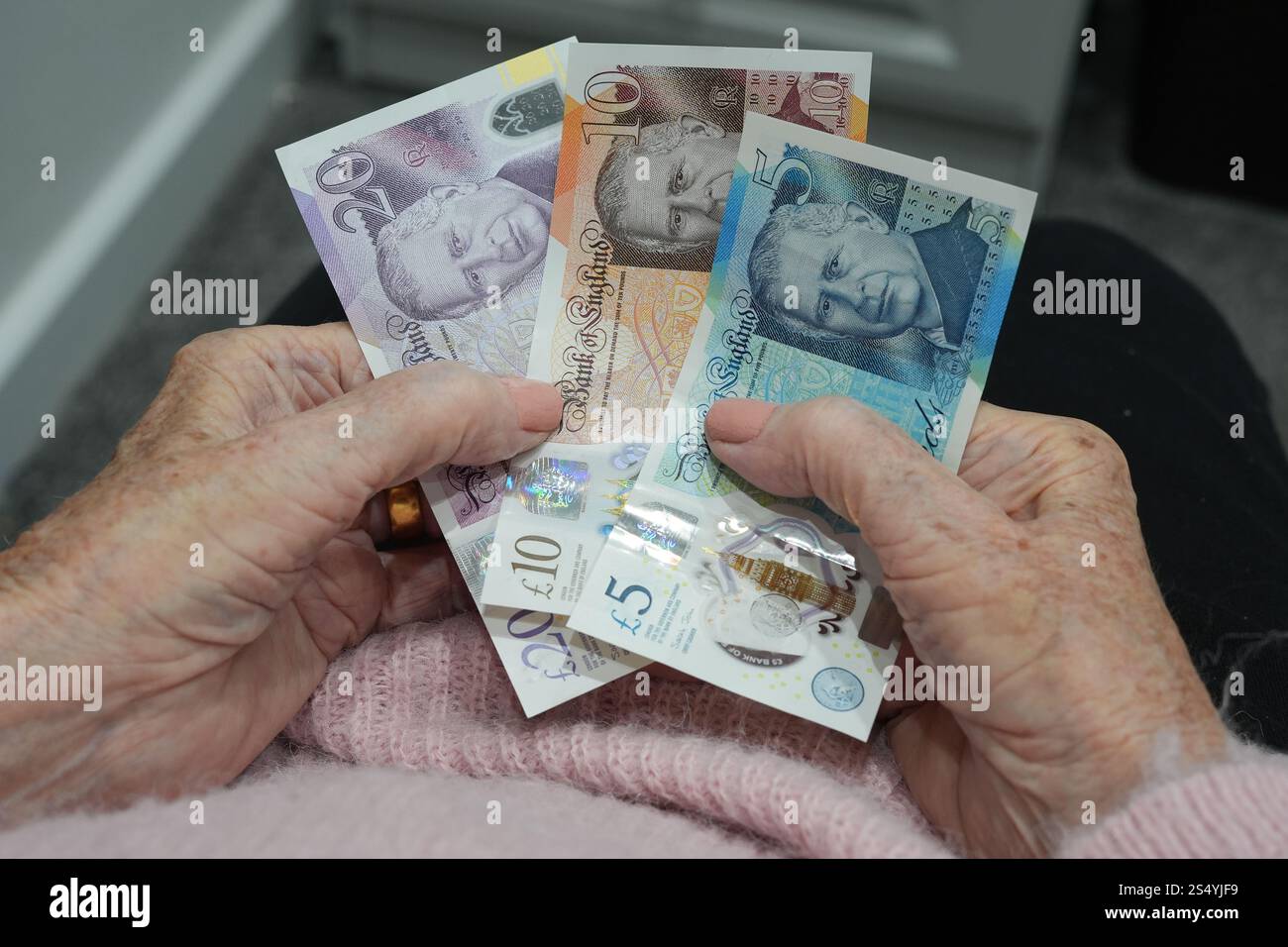 Picture posed by model An old age pensioner holding bank notes at home ...