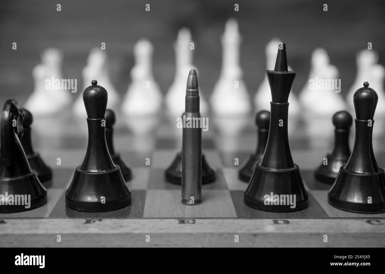 Black and white closeup photo of bullet in row of chess pieces ...