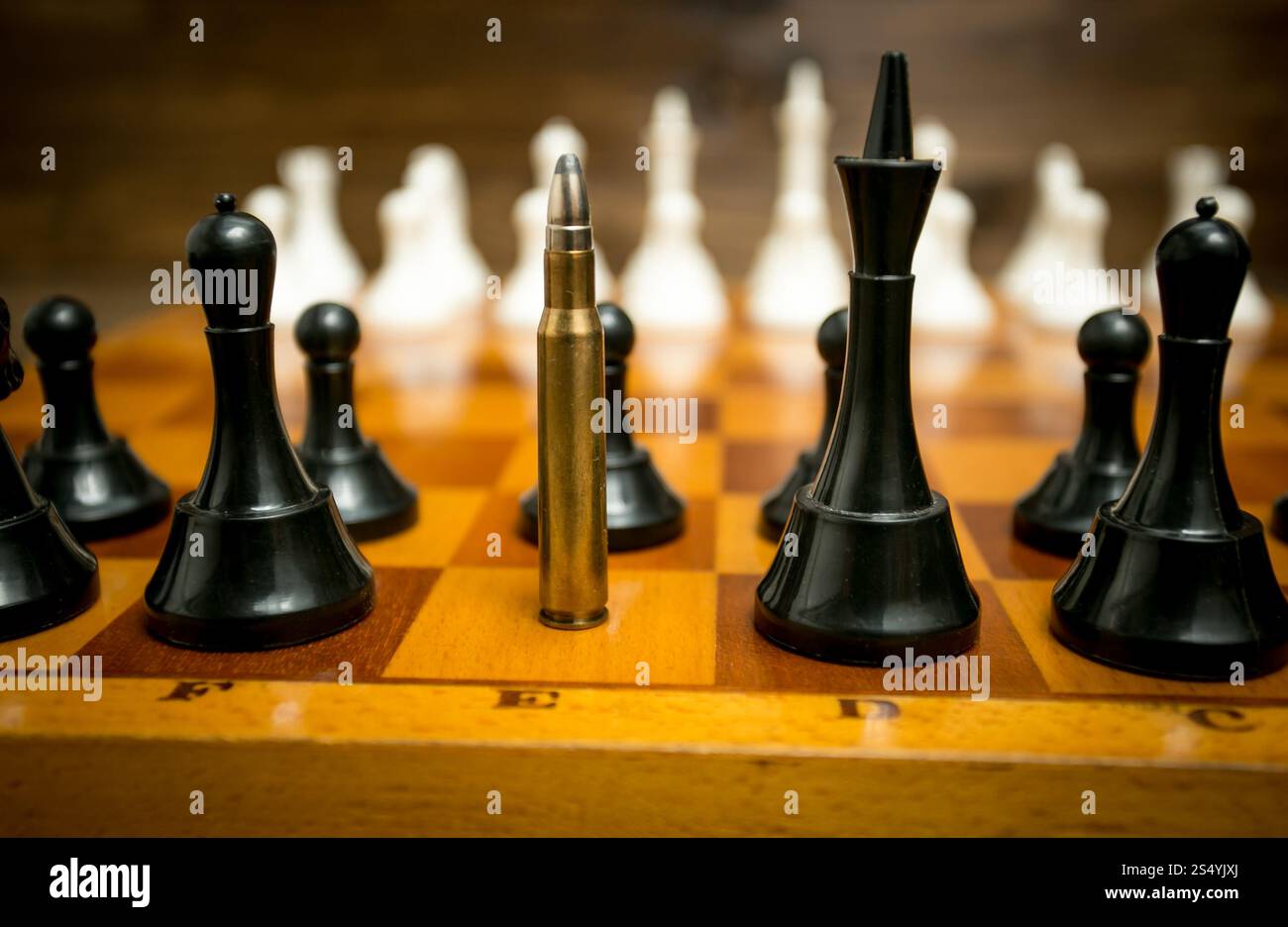 Big riffle bullet in row of black chess pieces. Concept of gun power ...