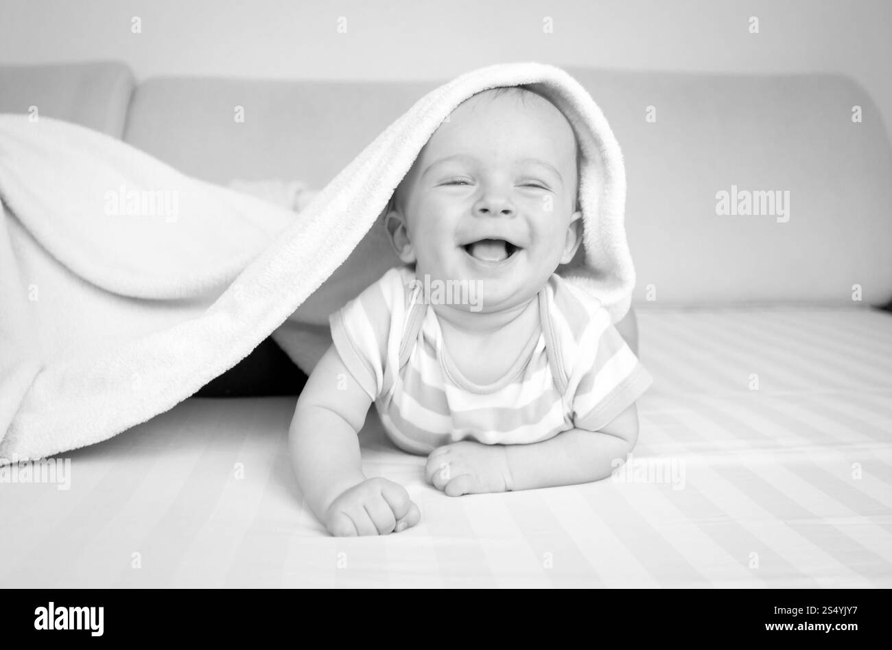 Black and white portrait of cute baby boy lying on bed under the ...