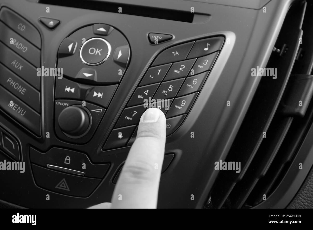 Closeup black and white image of woman pressing button on car dashboard ...
