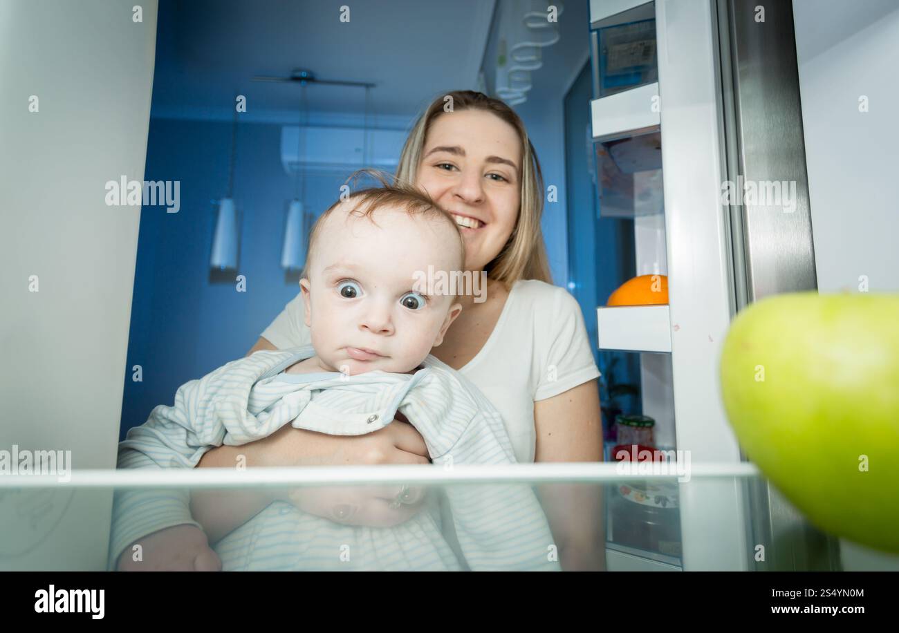 Mother holding baby and taking green apple from apple. View from inside ...