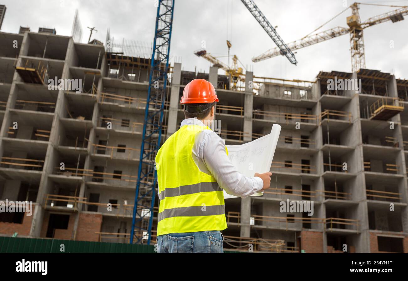 Architect in hardhat pointing at building under construction Stock ...