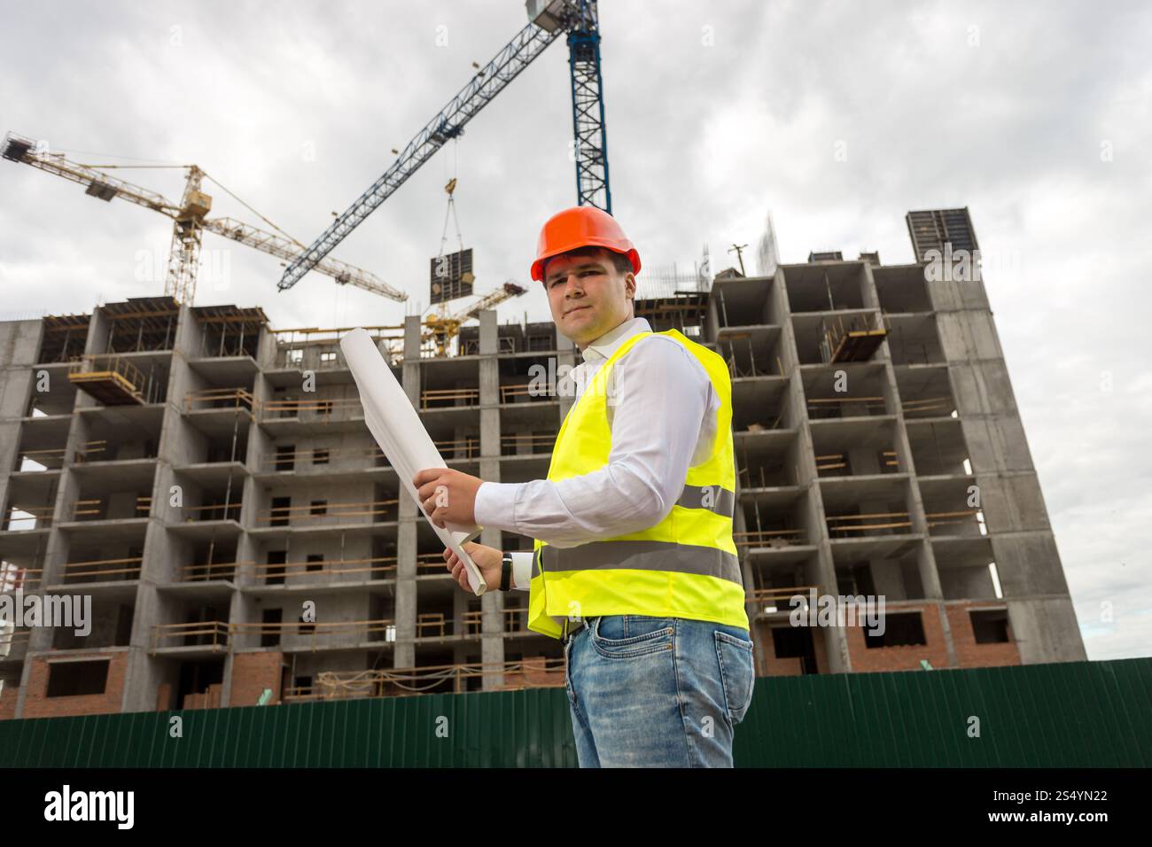 Engineer in red hardhat standing on construction site and checking ...