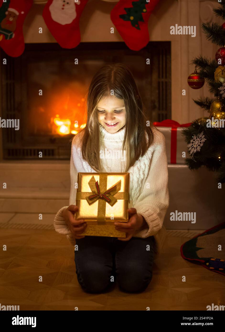 Cheerful girl opening box with Christmas present. Light and shiny ...