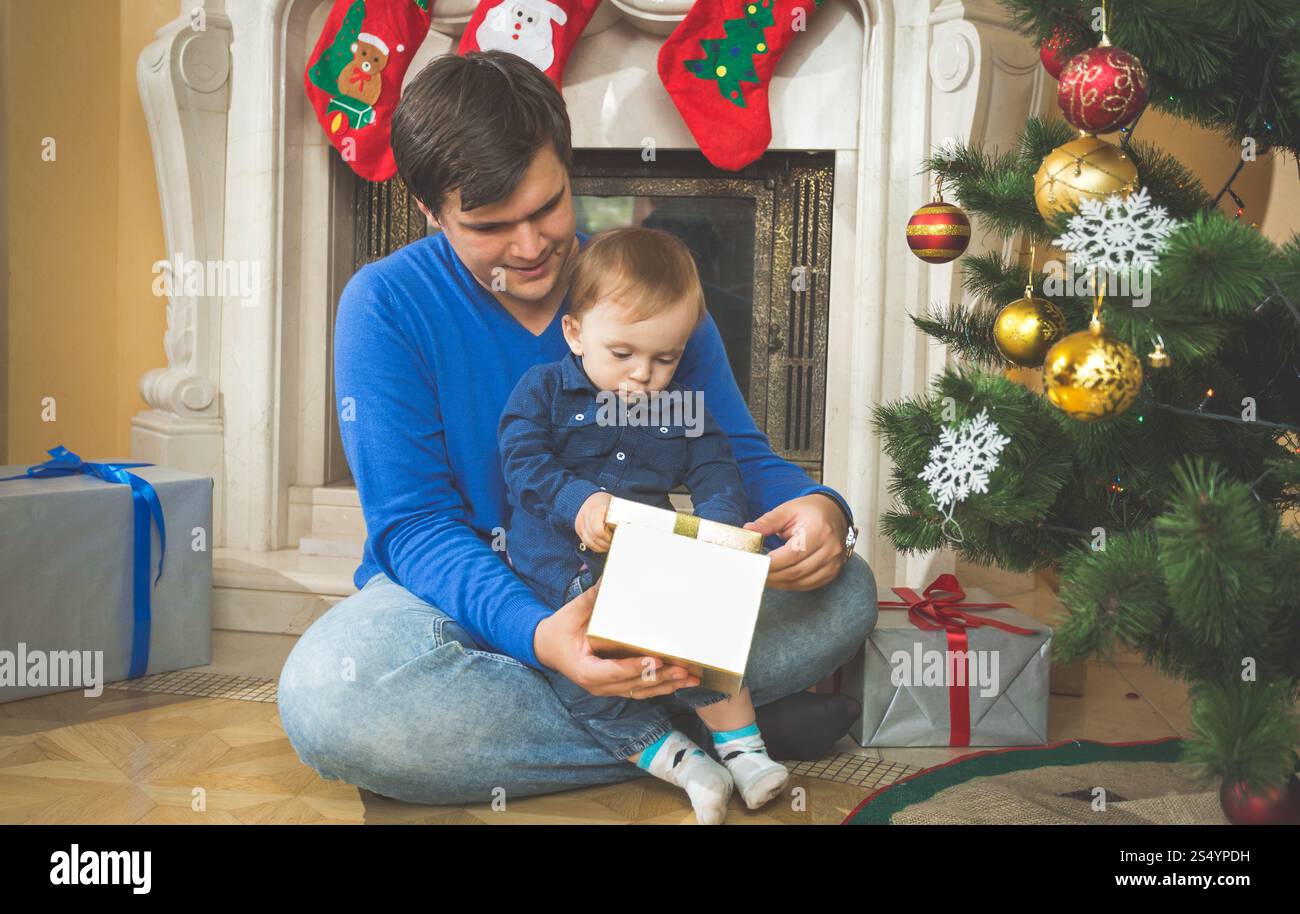 Young father and cute baby son opening Christmas gifts on floor Stock ...