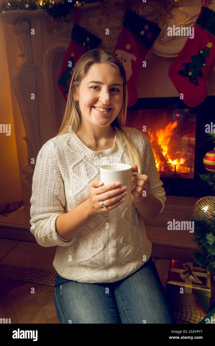 Portrait of beautiful young woman drinking tea at the fireplace Stock ...