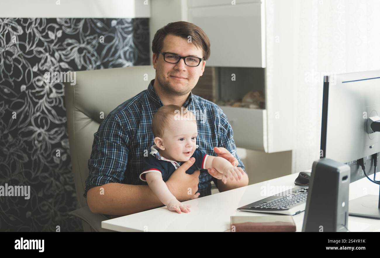 Father with his baby son working at office Stock Photo - Alamy