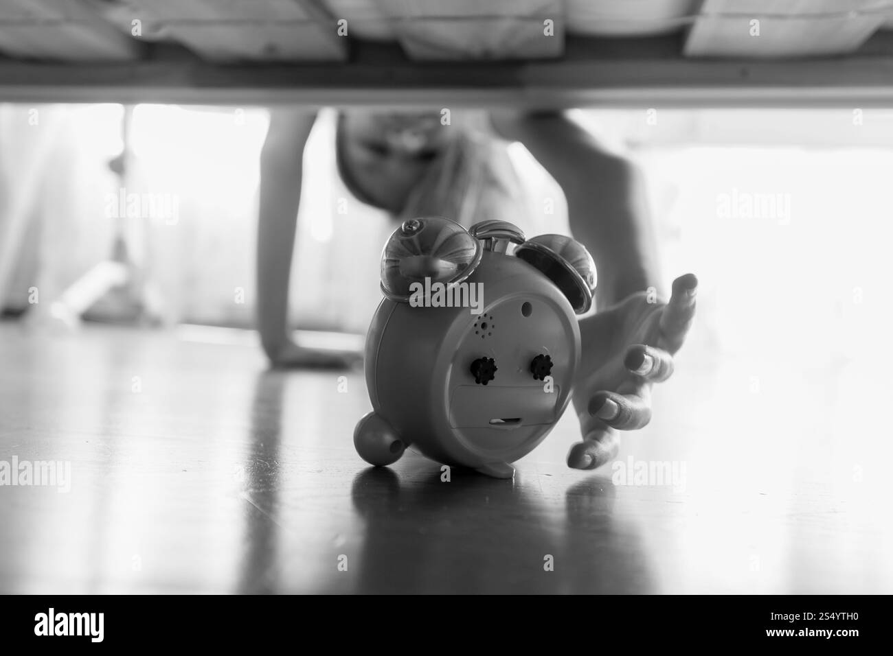 Black and white image of beautiful girl reaching for alarm clock under ...