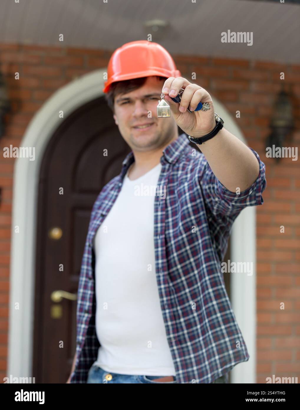 Construction worker holding keys from new house in hand Stock Photo - Alamy