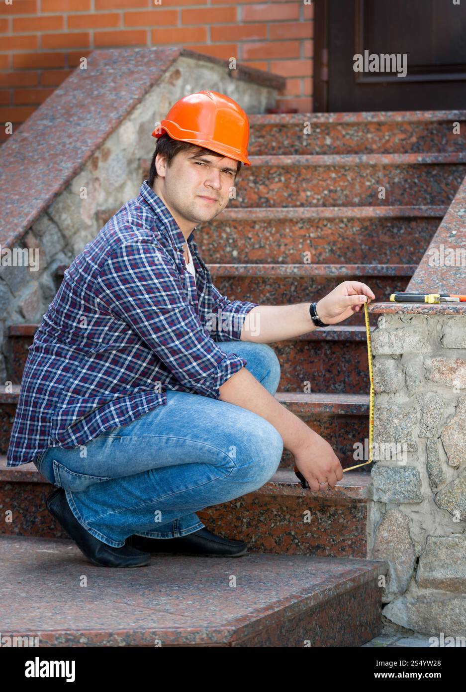 Smiling male worker measuring stone staircase with measuring tape Stock ...