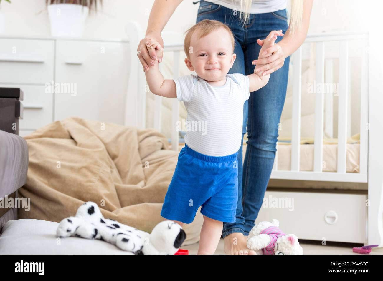 Adorable baby learning how to walk with mother at home Stock Photo - Alamy