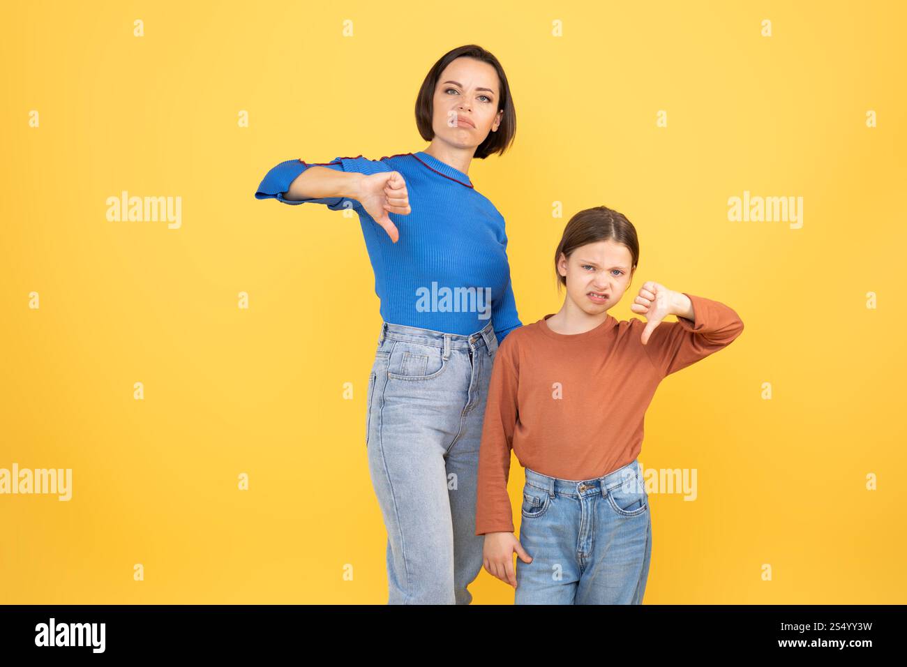 Mom and daughter express disapproval together against a bright yellow ...