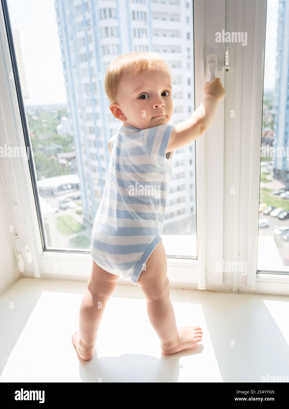 10 months old baby boy trying to open window Stock Photo - Alamy