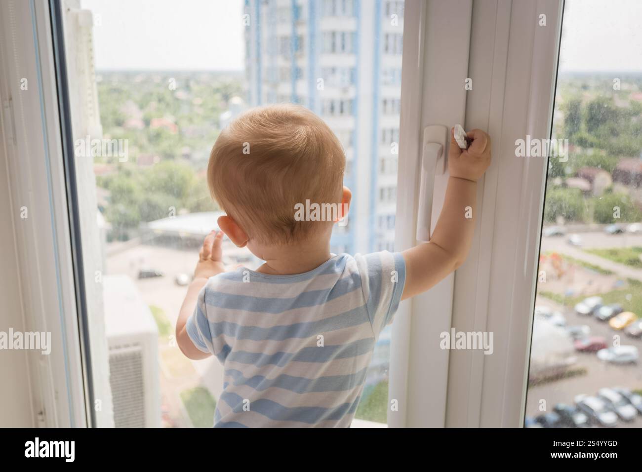 Baby in danger. Baby trying to open window and pulling its handle Stock ...