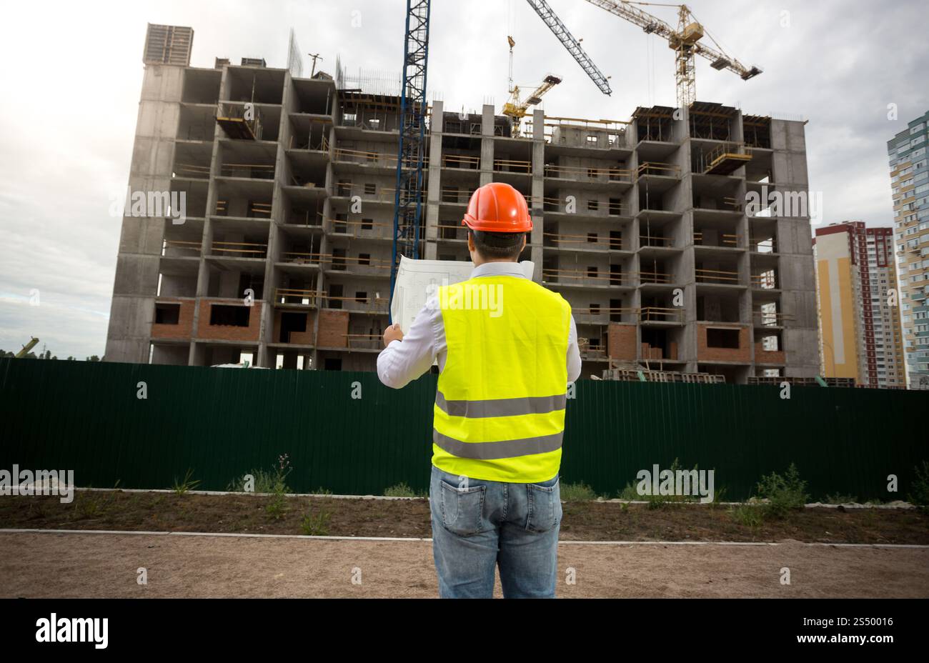 Young construction engineer reading blueprints at building site Stock ...