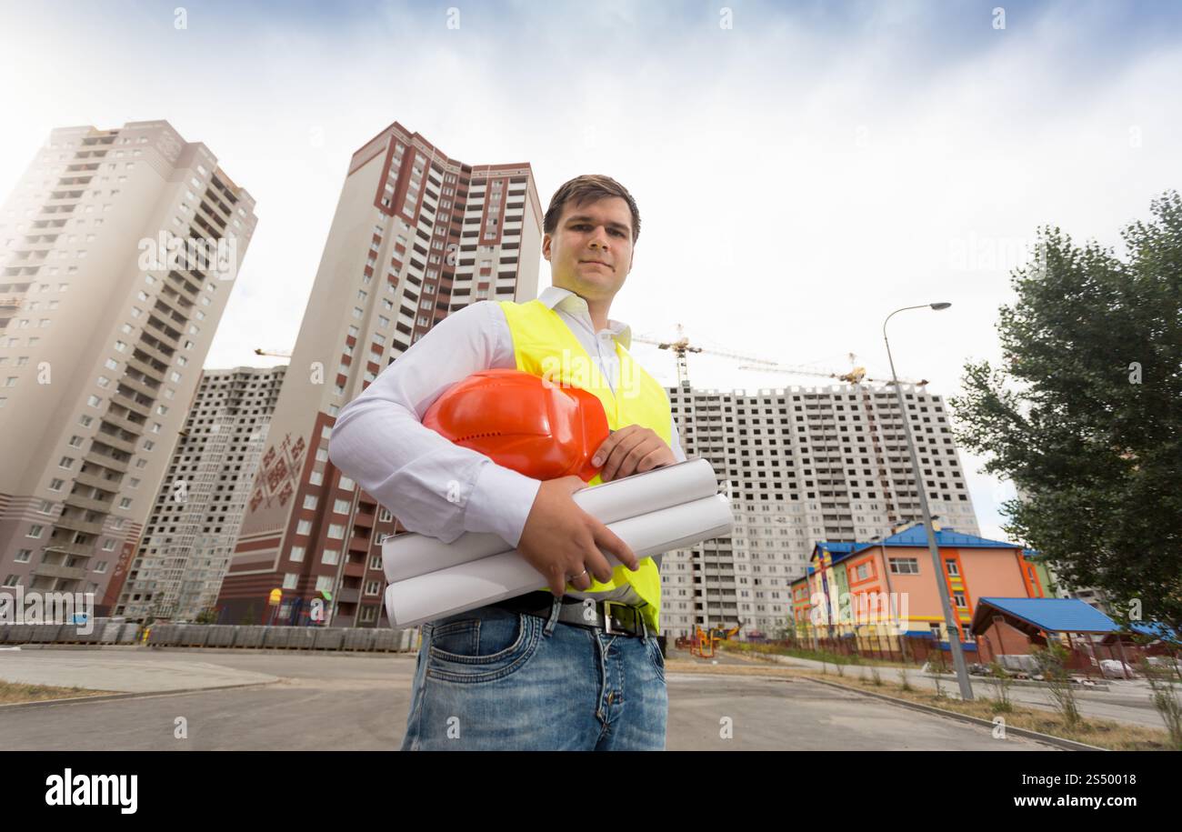 Portrait of engineer standing at new buildings with blueprints Stock ...