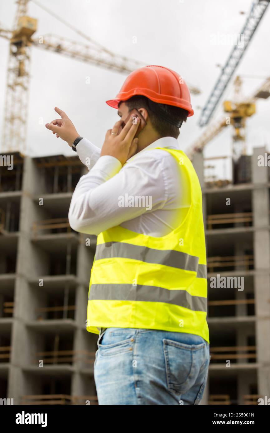 Construction engineer pointing with finger at building under ...
